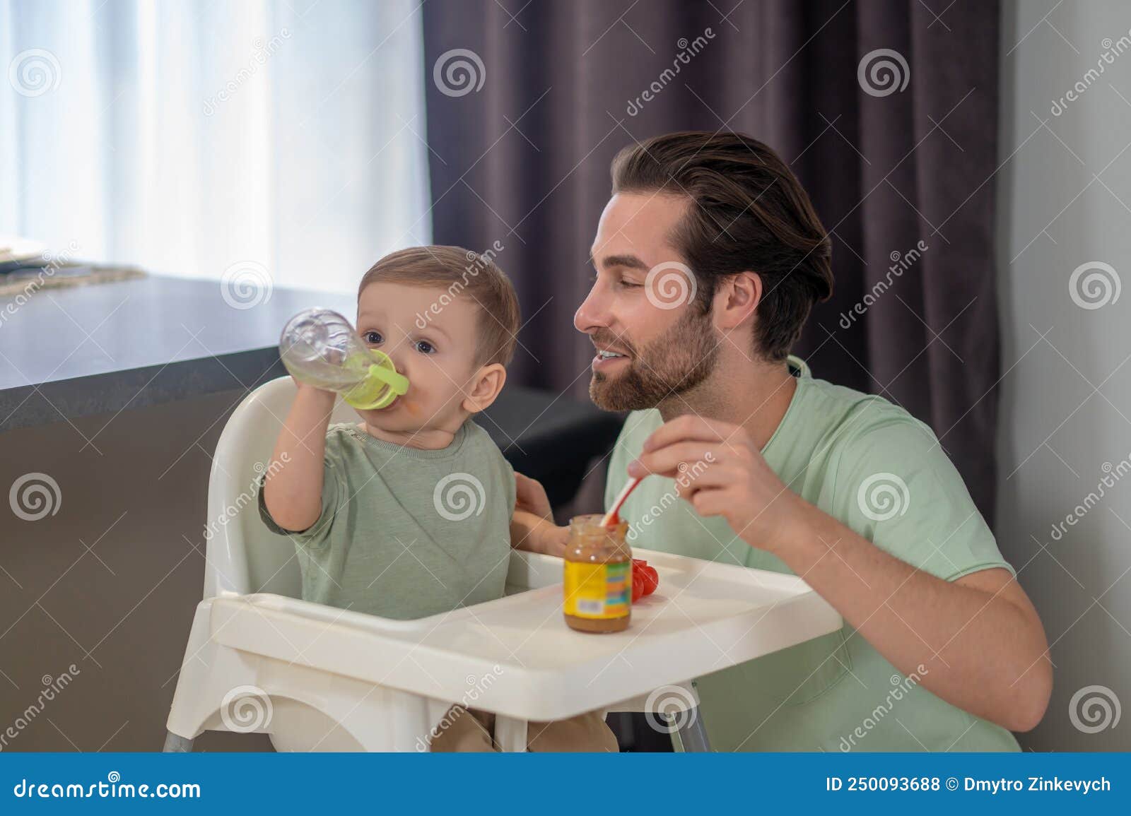 Cute Little Boy Drinking from His Bottle while Dad Feeding Him Stock ...