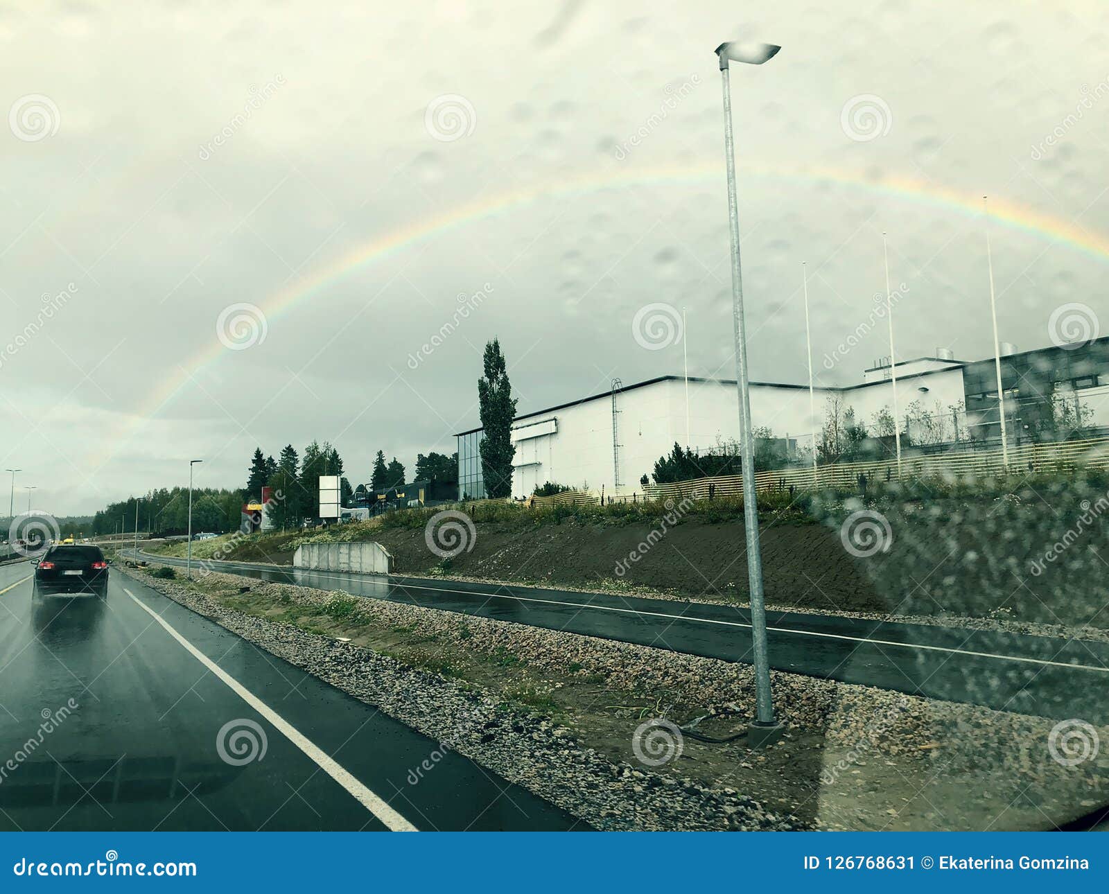 Drizzle on the Windshield while Driving in Rain. Wet Road and Rainbow ...