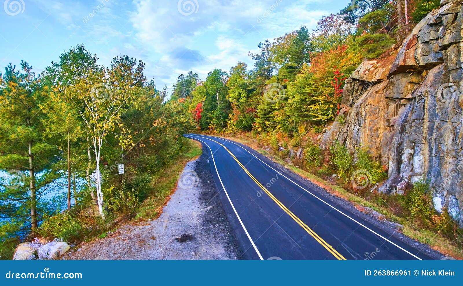 Drone Above Clean Road Going through Fall Forest with Lake and Cliffs ...