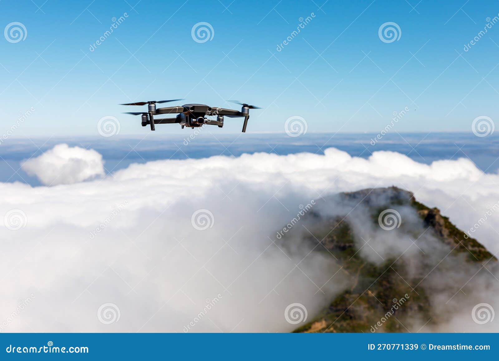 Drone with Camera Flying Over the Mountain Peak and White Clouds. Stock ...
