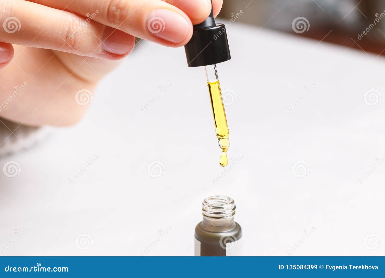 A Drop of Cosmetic Oil Drips from the Pipette into the Bottle Stock ...