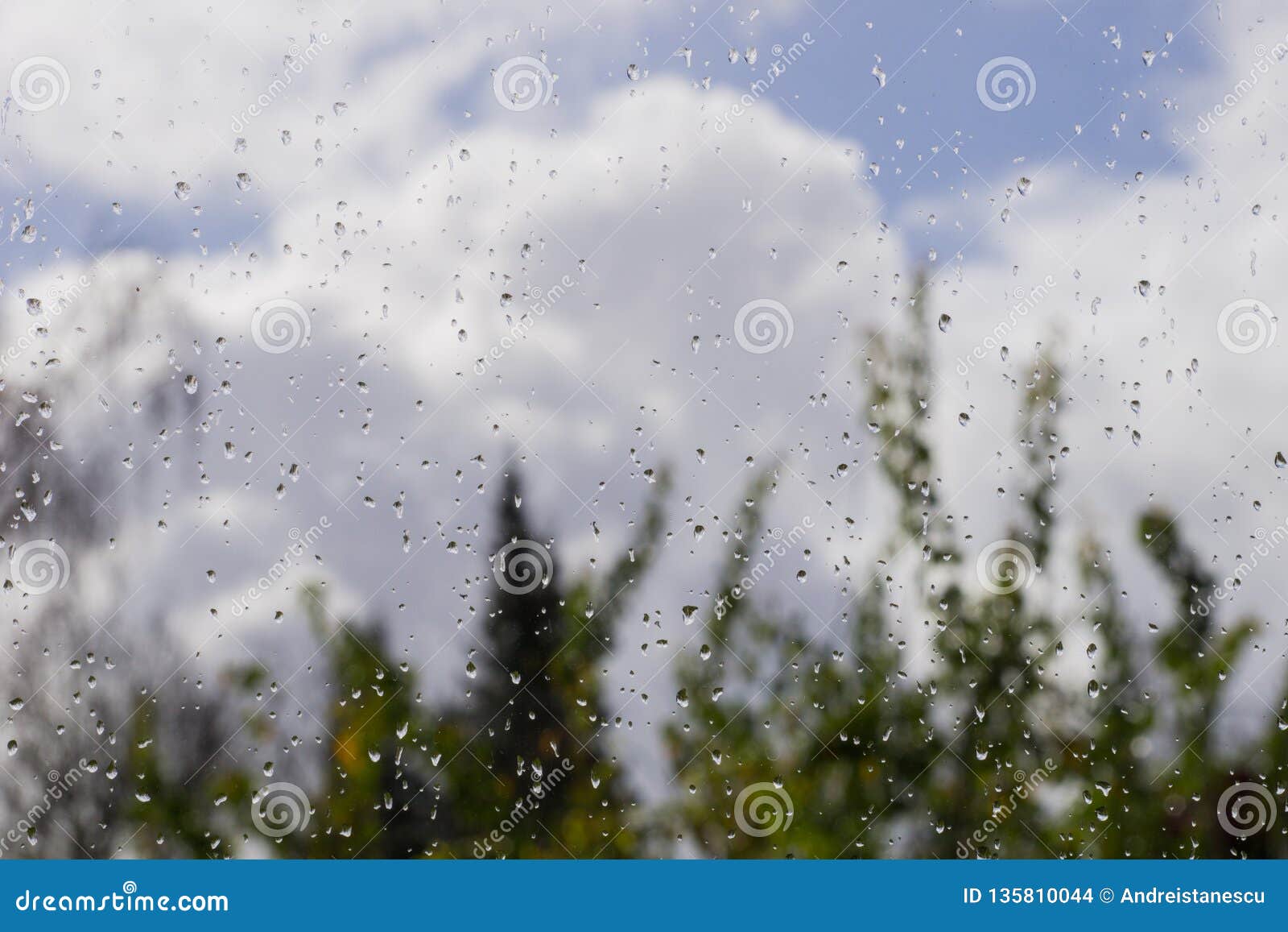 Drops of Rain on the Window; Blurred Trees and Clouds in the Background ...