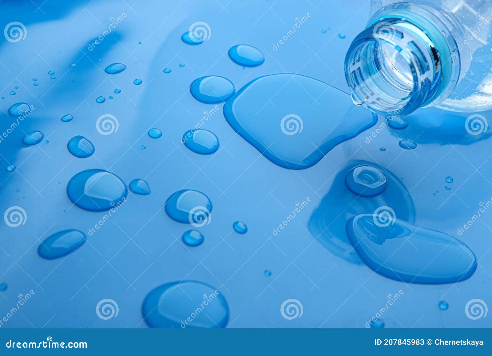 Drops of Spilled Water and Plastic Bottle on Blue Background, Closeup ...