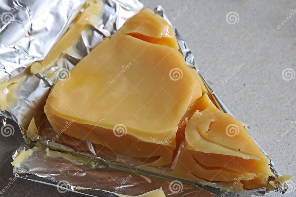 DRY CRACKED PROCESSED CHEESE WEDGE in a FOIL WRAPPING Stock Photo ...