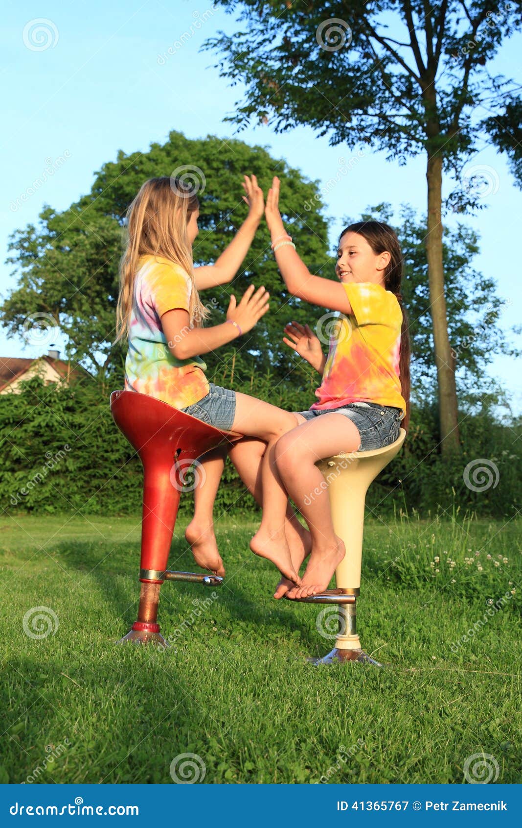 Duas Meninas Que Jogam O Jogo Ao Sentar Se Em Cadeiras Da Barra Imagem