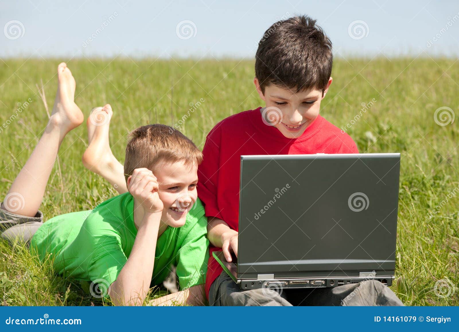 Due Ragazzi Con Il Computer Portatile Sull'erba Immagine Stock ...