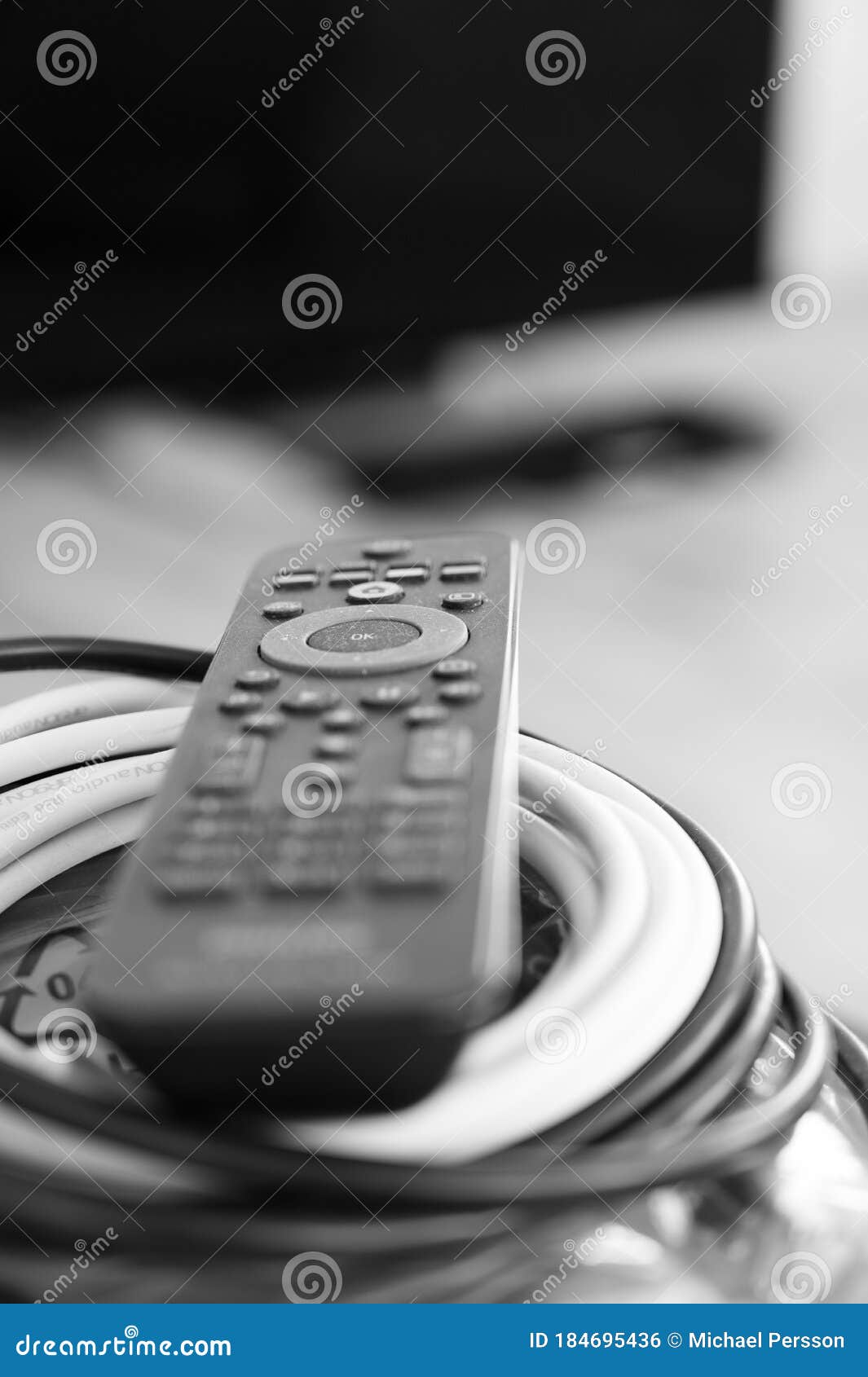 A Dusty Remote Control Placed on Some Cables with a TV Visible in the ...
