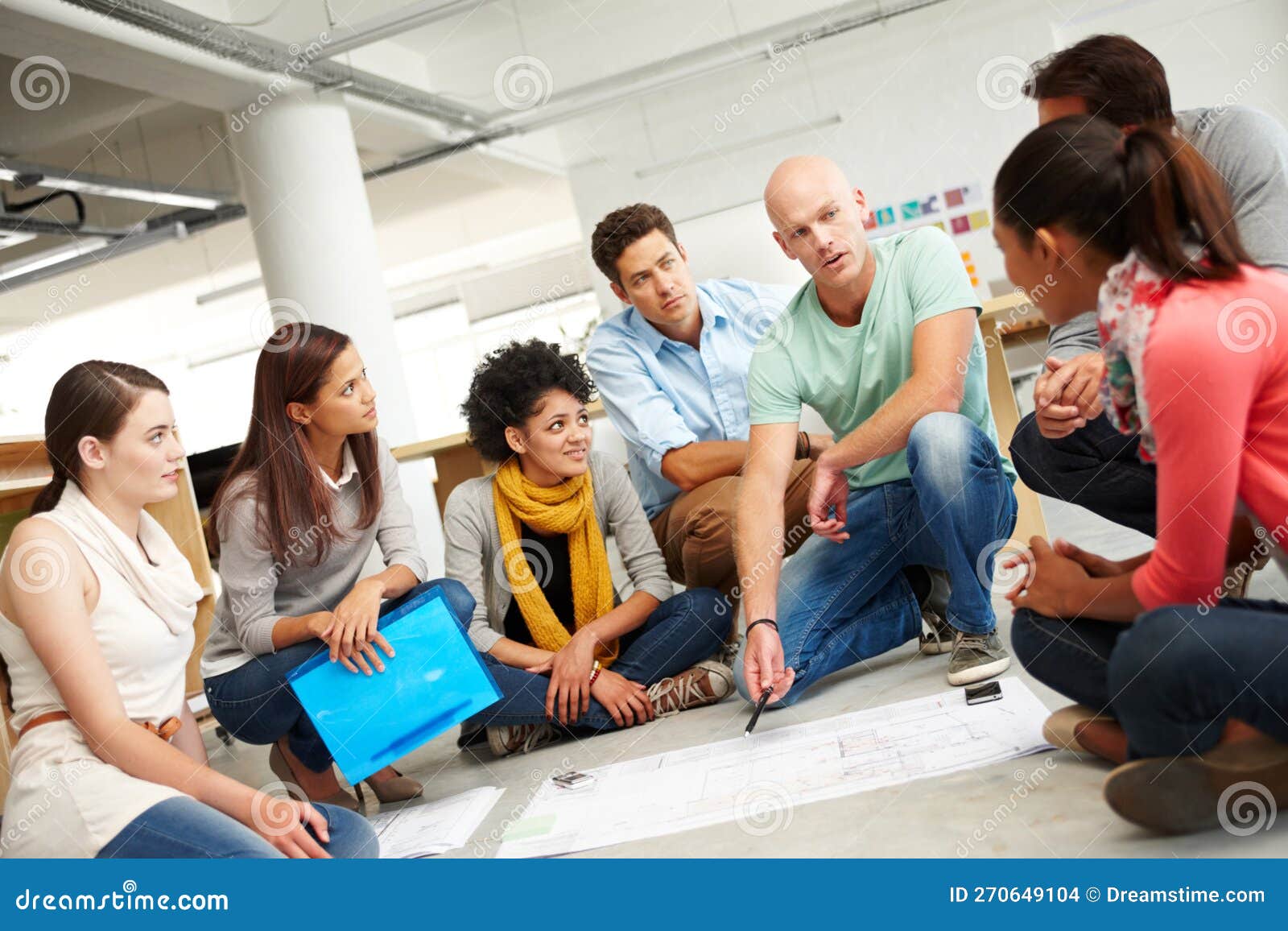 Dynamic Designers. a Group of Multi-ethnic Creatives Huddled Together and Listening To the ...