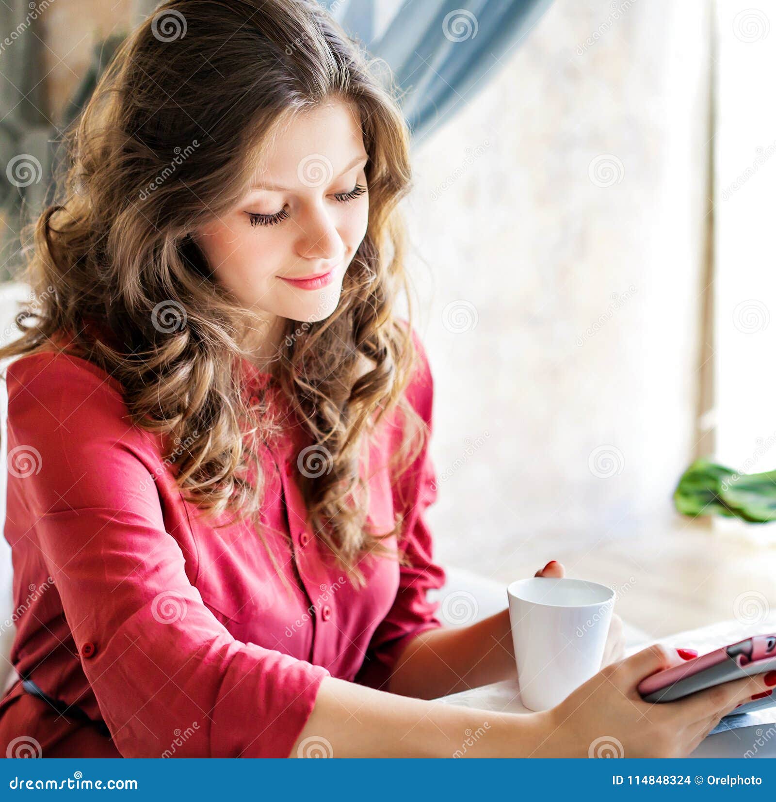 Young Beautiful Woman Sitting at the Table in a Cafe and Using Tablet ...