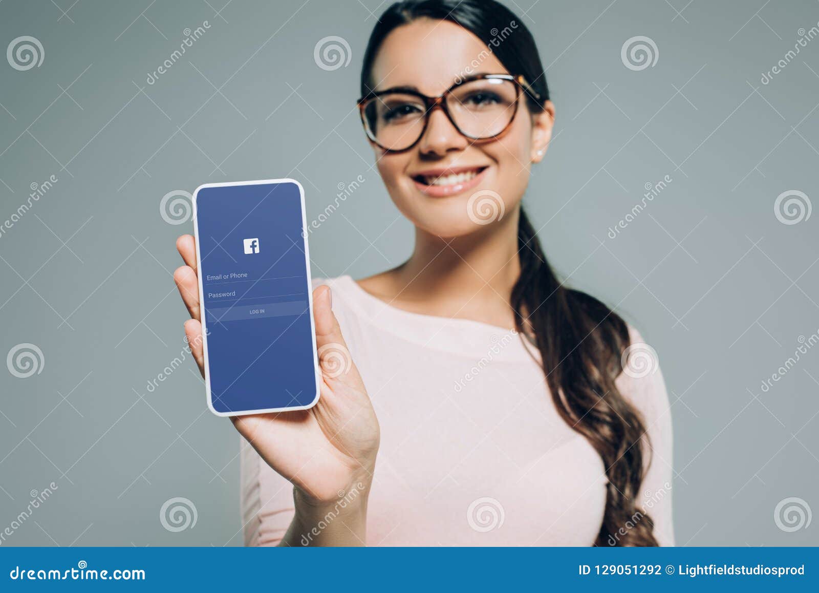 Beautiful Smiling Girl Presenting Smartphone with Facebook App ...
