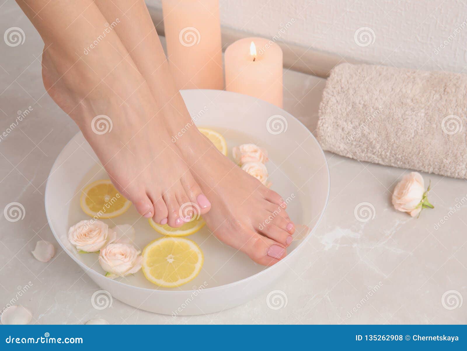 Woman Putting Her Feet into Bowl with Water, Roses and Lemon Slices on ...