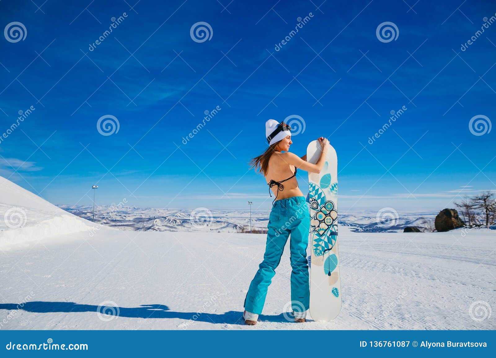 A Woman with a Bare Back with a Snowboard Stands with Her Back To the ...