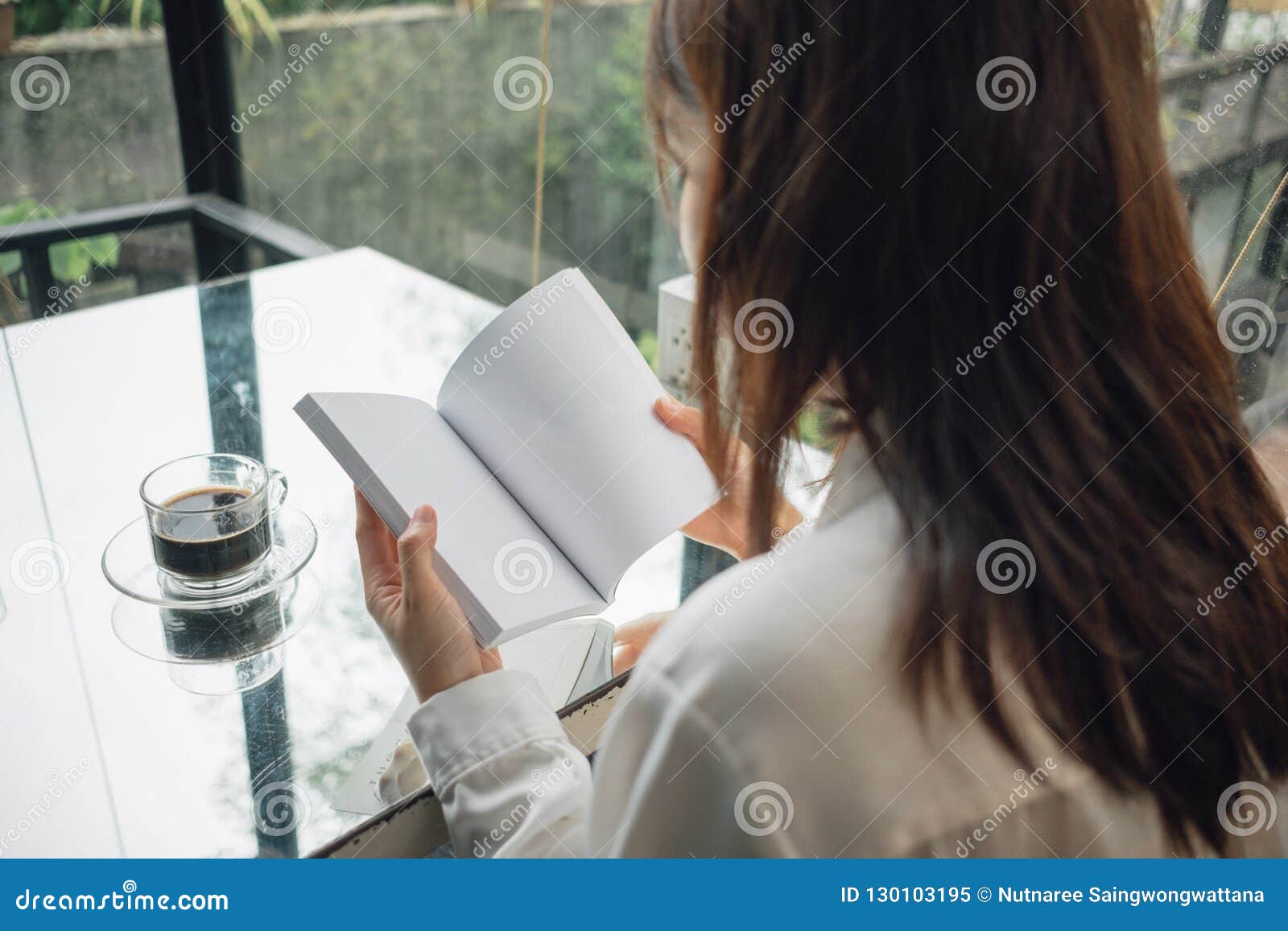Young Woman Sitting Alone and Reading Book in Restaurant with Co Imagen ...