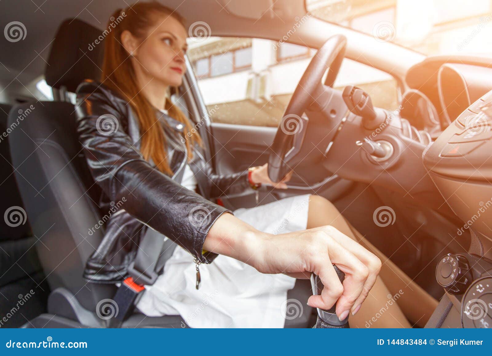 Young Woman in Leather Jacket and White Dress Driving a Car Fotografia ...