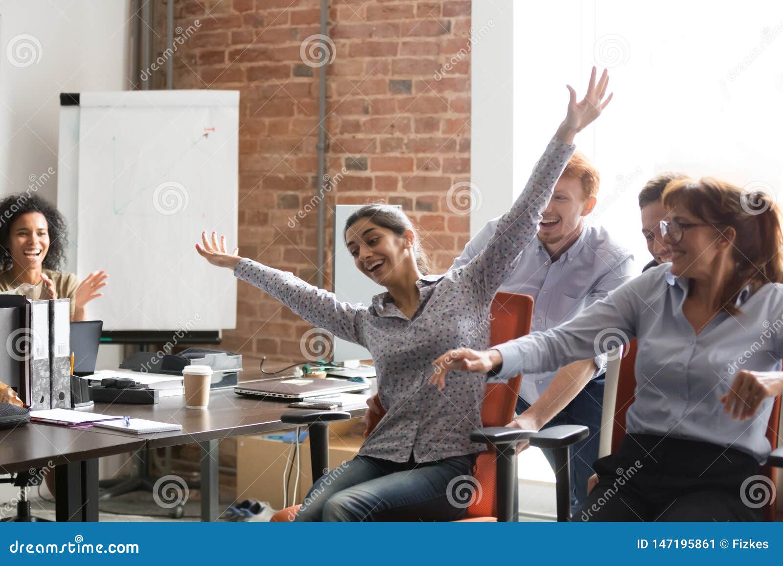 Excited Diverse Employees Have Fun Riding Chairs in Office Stock ...