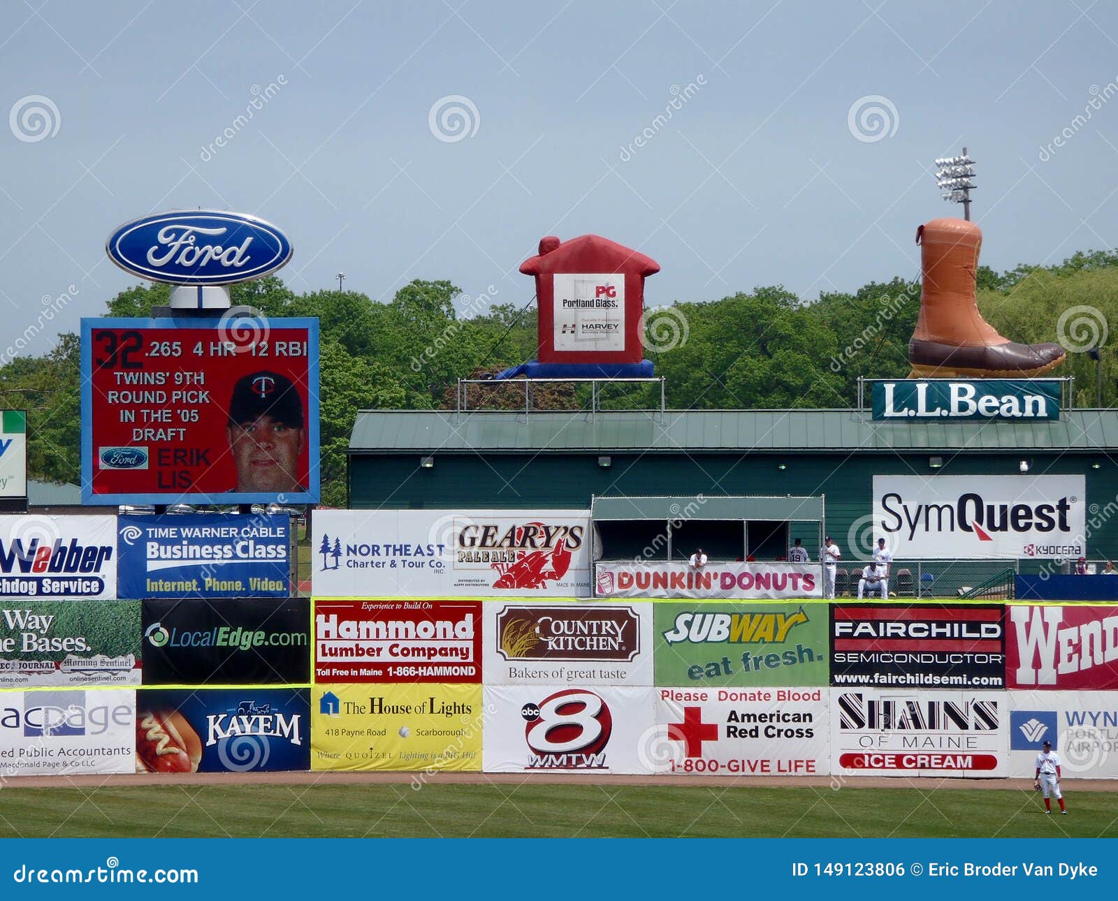 Baseball Player Stands in the Outfield with Ads on Wall Including LL ...