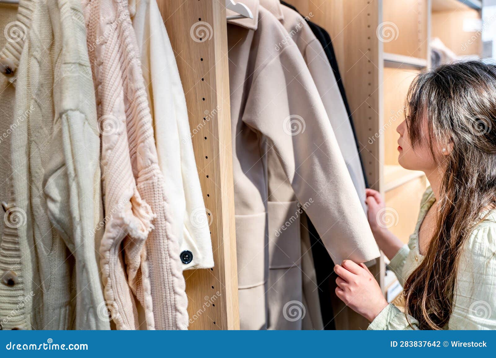 East Asian Female Standing among an Array of Clothes in a Store Stock ...