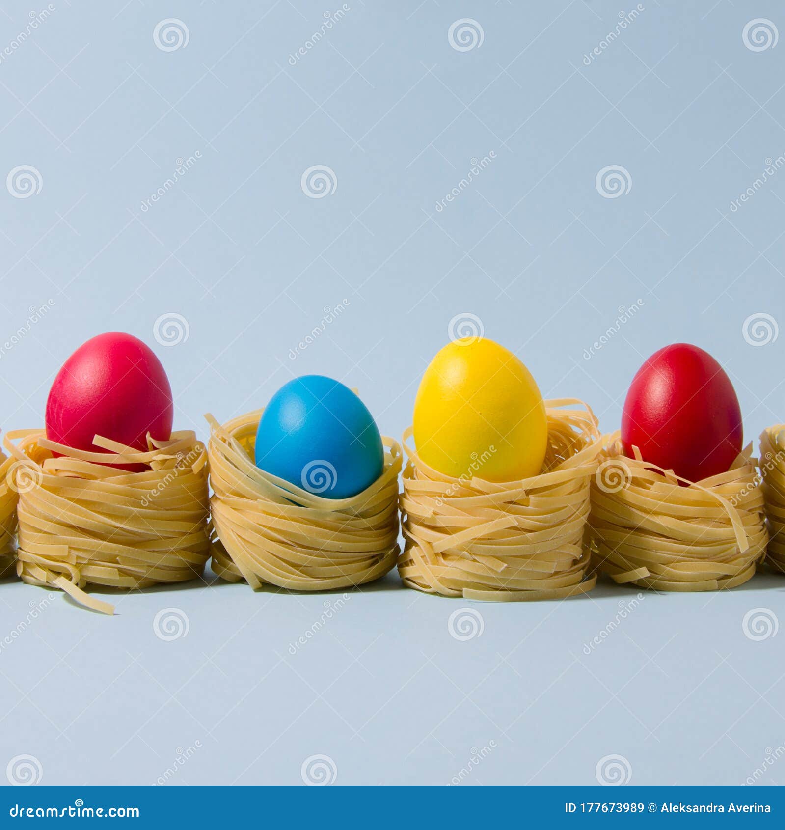 Easter Eggs of Red, Blue, Yellow Colors are in Macoron Nests on a Blue ...
