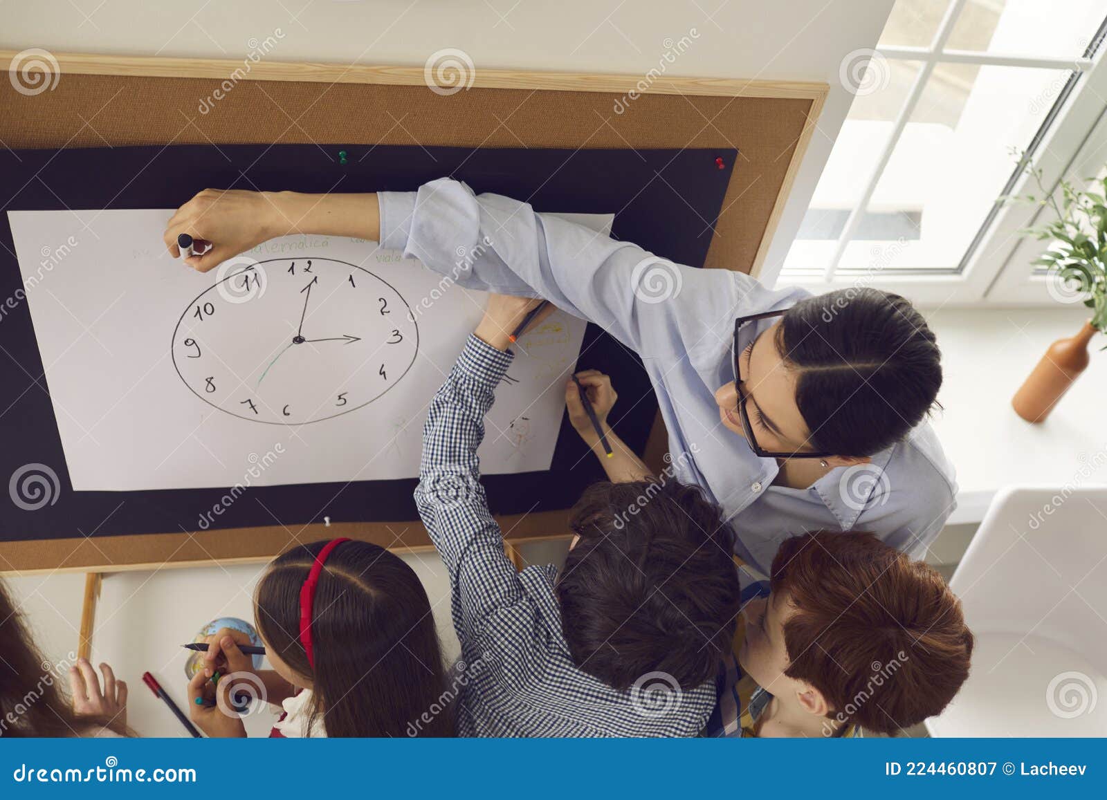 Female Teacher Explaing Clock Time To Elementary Student Children in ...