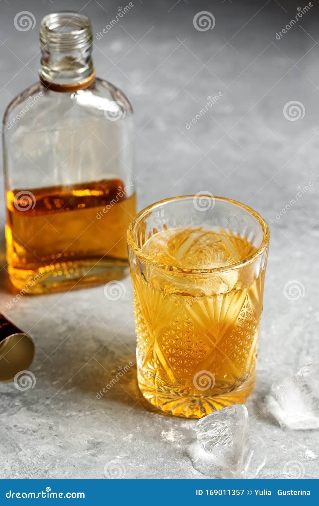 Een Glas Whisky Met Ijs En Een Halve Lege Fles Op Een Grijze Betonnen ... Een Glas Whisky Met Ijs En Een Halve Lege Fles Op Een Grijze Betonnen ...