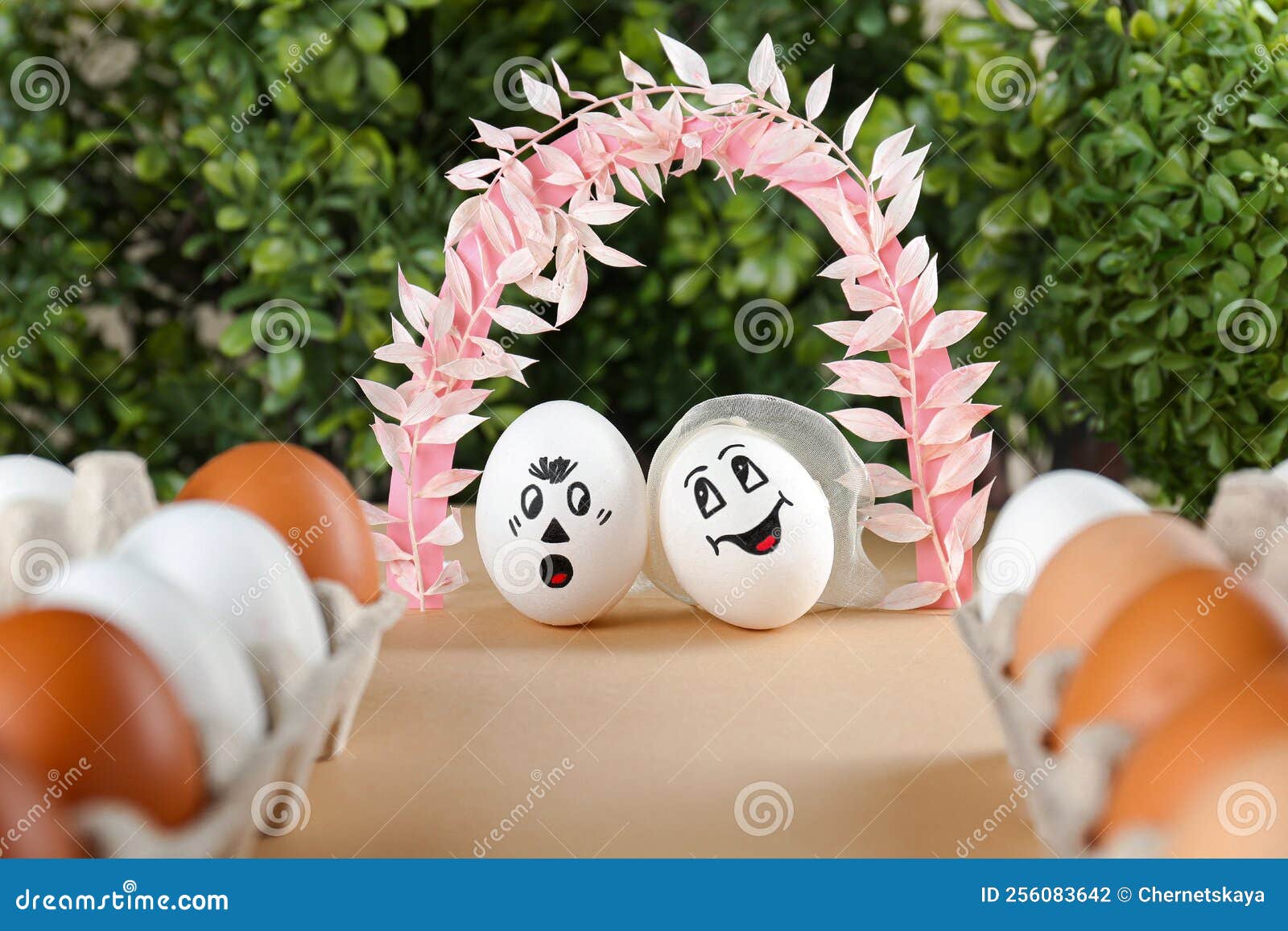 Eggs with Drawn Faces As Bride and Groom Under Decorative Arch on Table ...