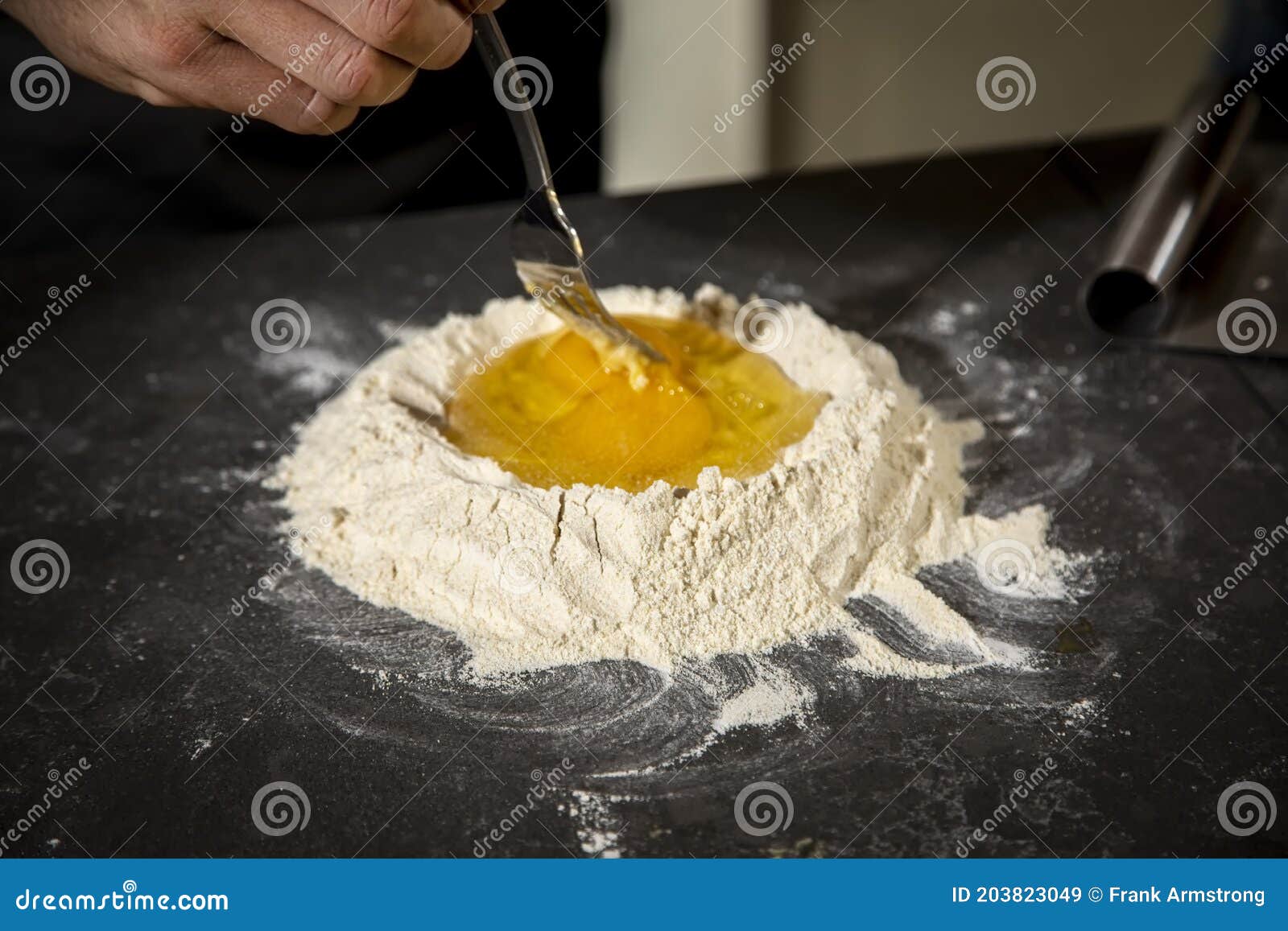 Eggs in Mound of Flour with a Hand and Fork Mixing Ready To Make Dough ...