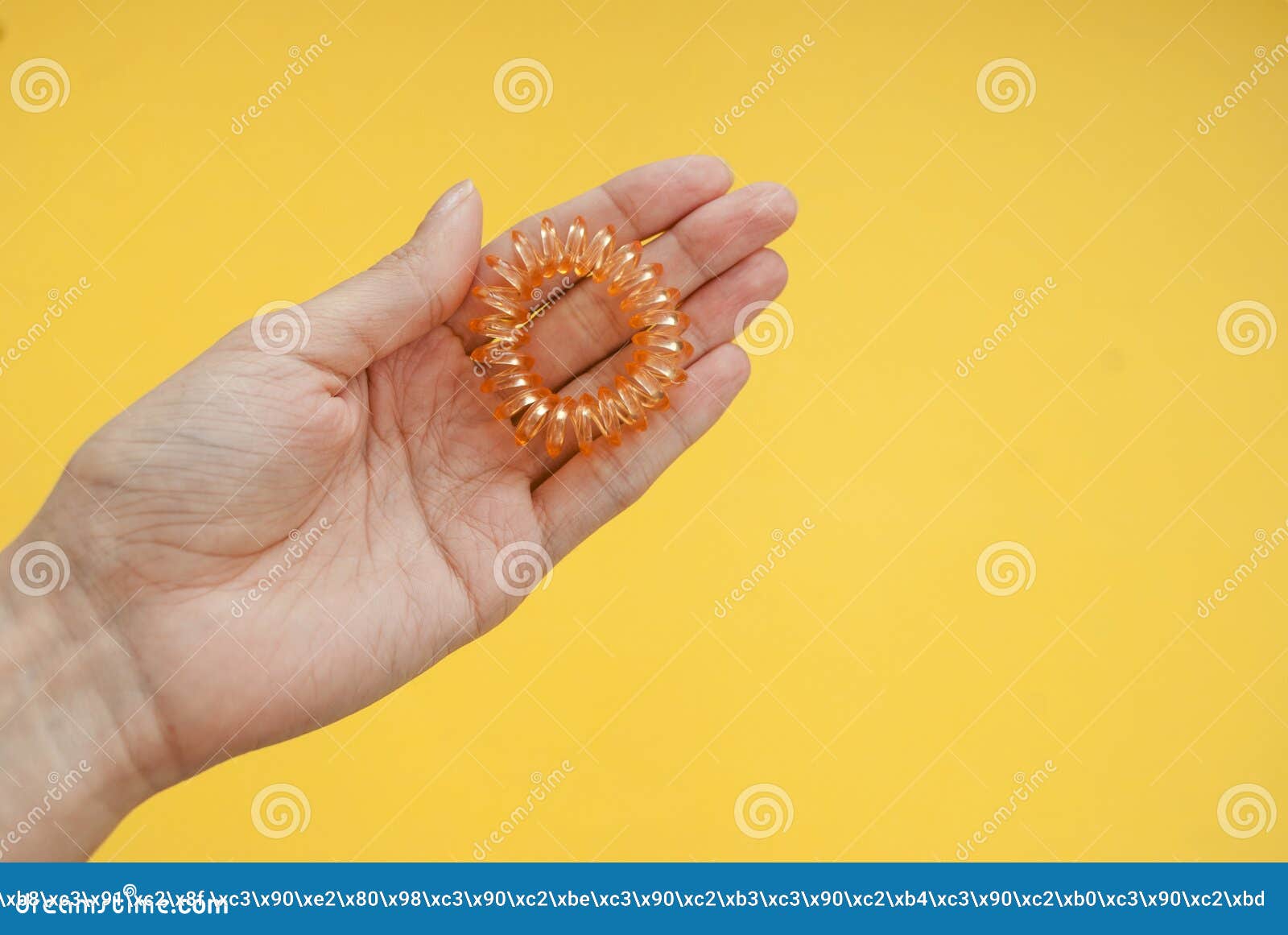 Elastic Band Spring for Hair in Hands, Orange on a Yellow Background ...