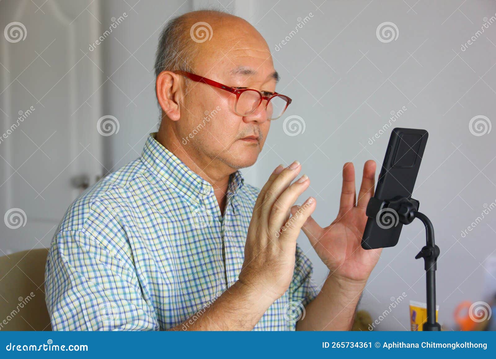 An Elderly Asian Man Explaining the Functionality or Features of an ...