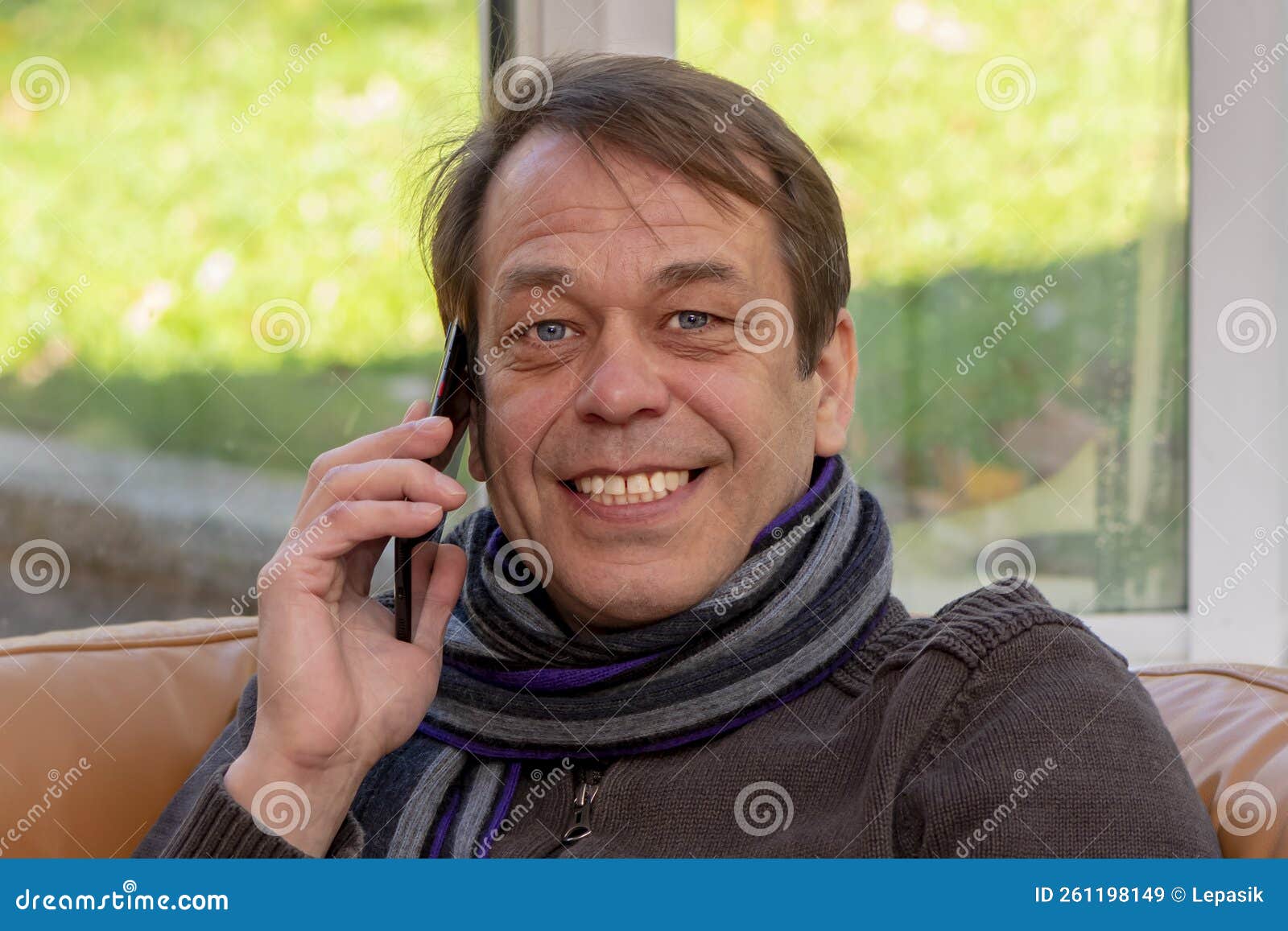 An Elderly Man in a Scarf is Talking on a Smartphone Sitting on the ...
