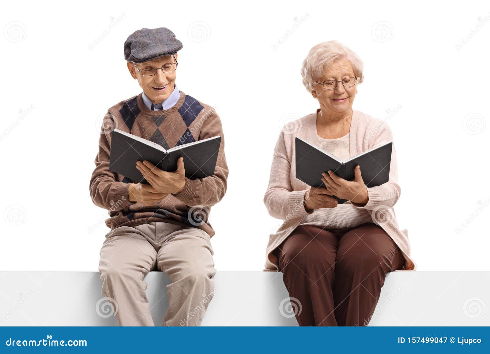Elderly Man And Woman Seated On A Panel Reading Books Stock Image