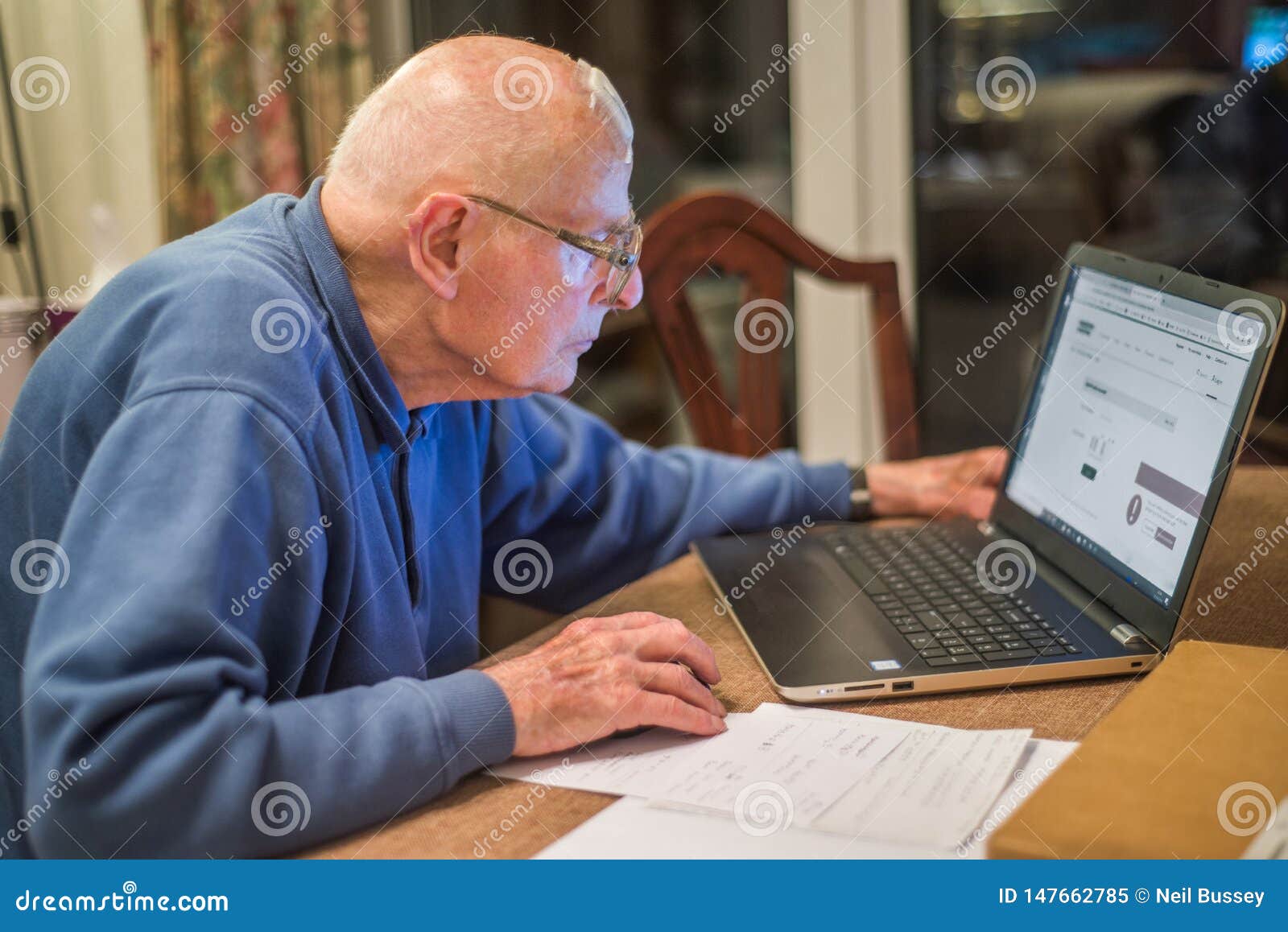 Elderly Person Using a Laptop Computer To Check His Share Portfolios ... Elderly Person Using a Laptop Computer To Check His Share Portfolios ...