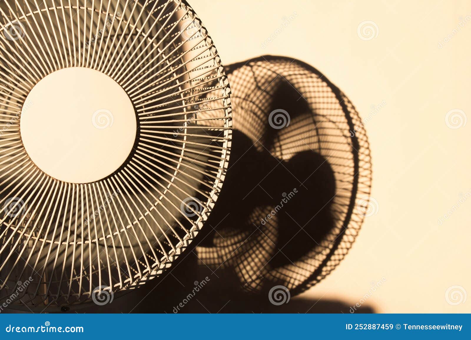 An Electric Fan with Blurred Blades Moving Casting a Blurry Shadow on a ...