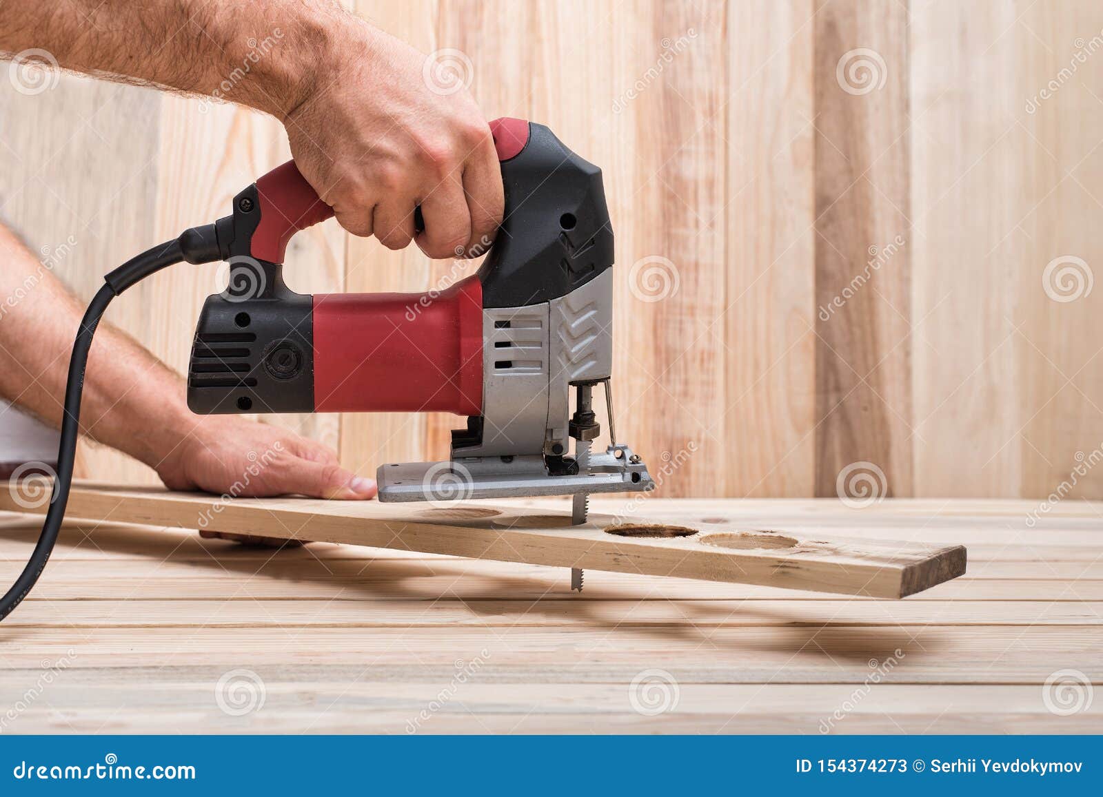 Electric Jigsaw in Male Hand. Processing of Workpiece on Light Brown ...