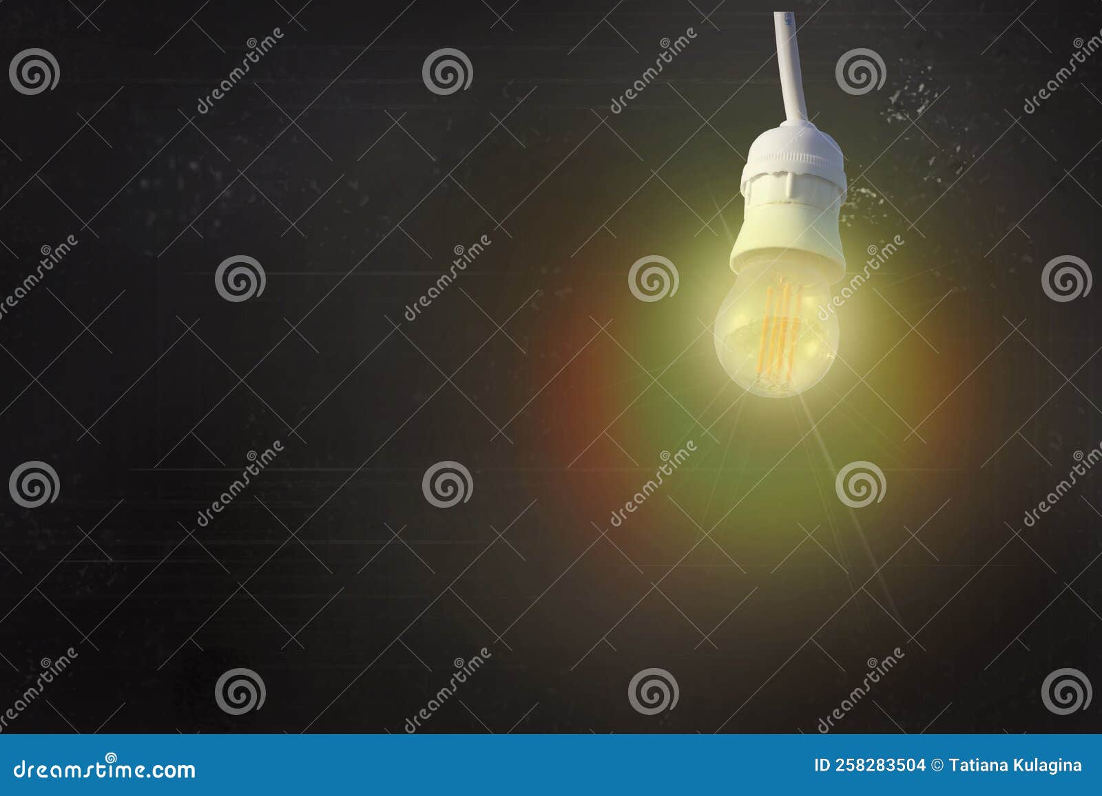 An Electric Light Bulb Shines with a Dim Light on a Gray Background ...