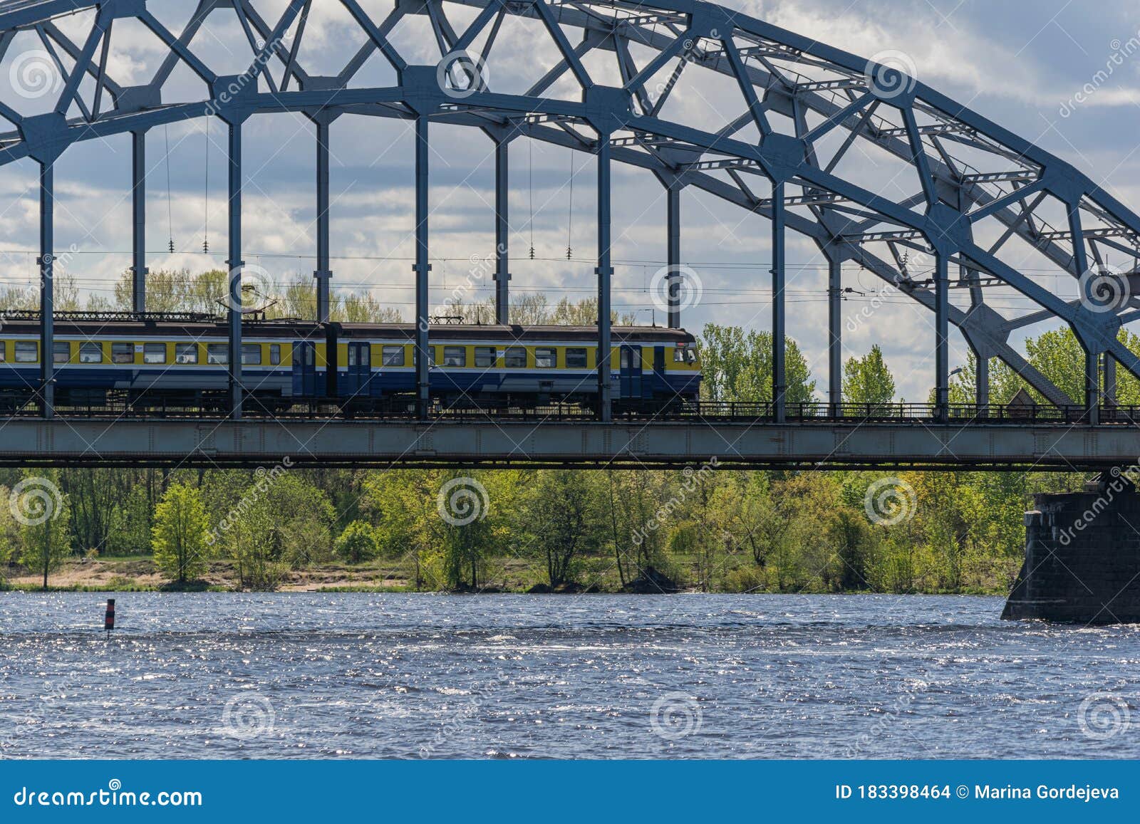 An Electric Train Rides on a Bridge Crossing a River. Passenger Train ...