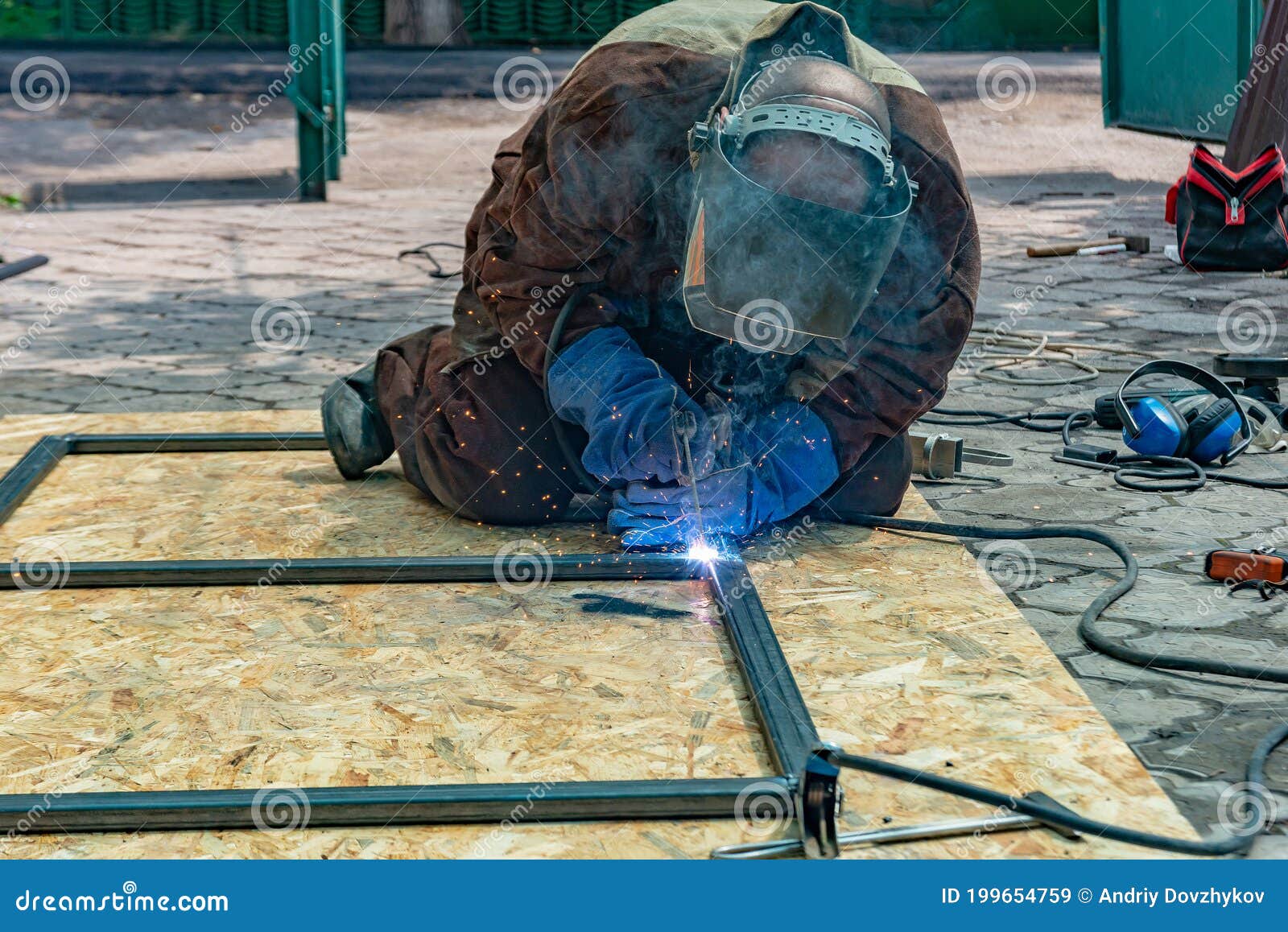 An Electric Welder Makes a Metal Structure by Connecting a Pipe with ...