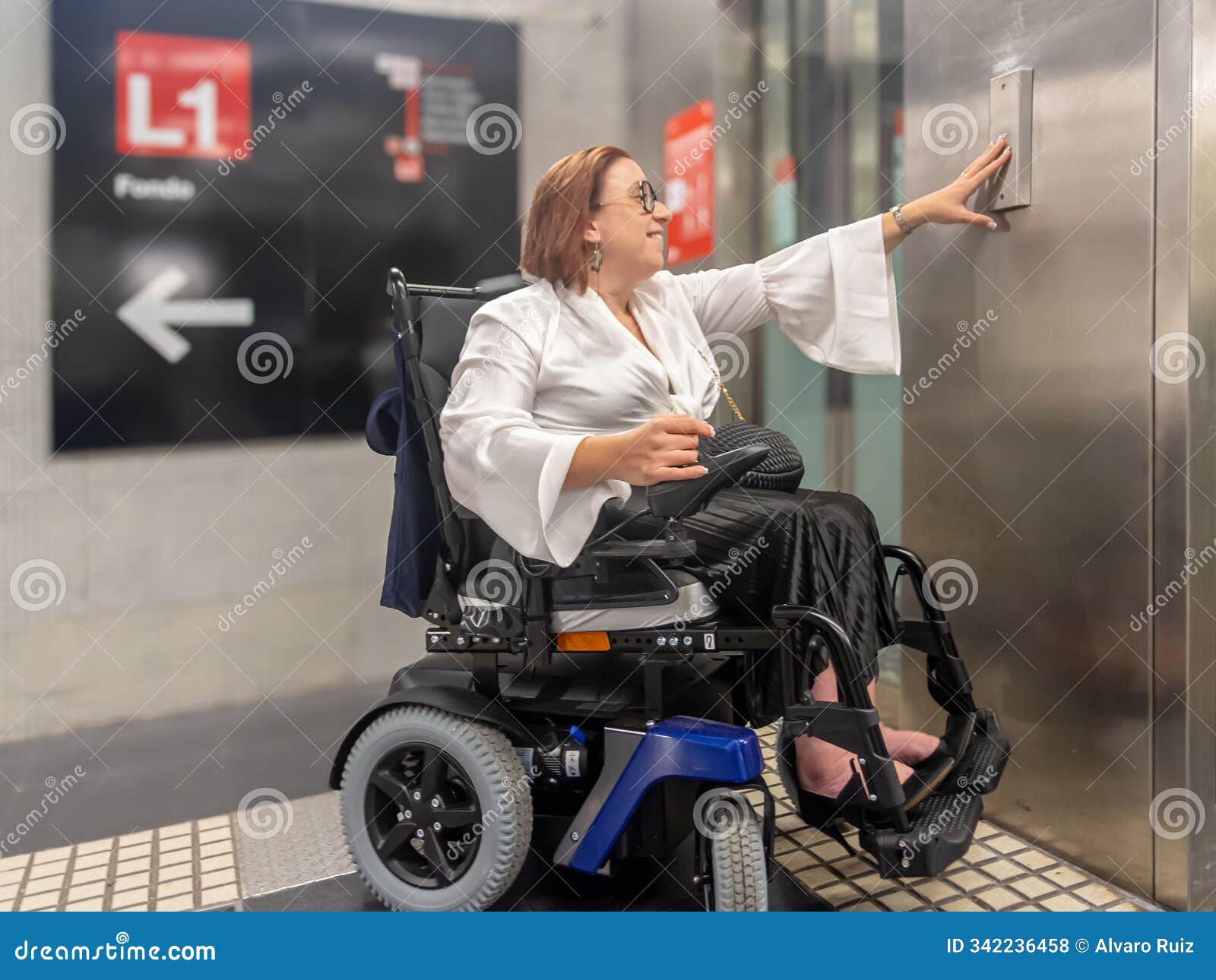 Electric Wheelchair User Pressing Elevator Button in Metro Stock Photo ...