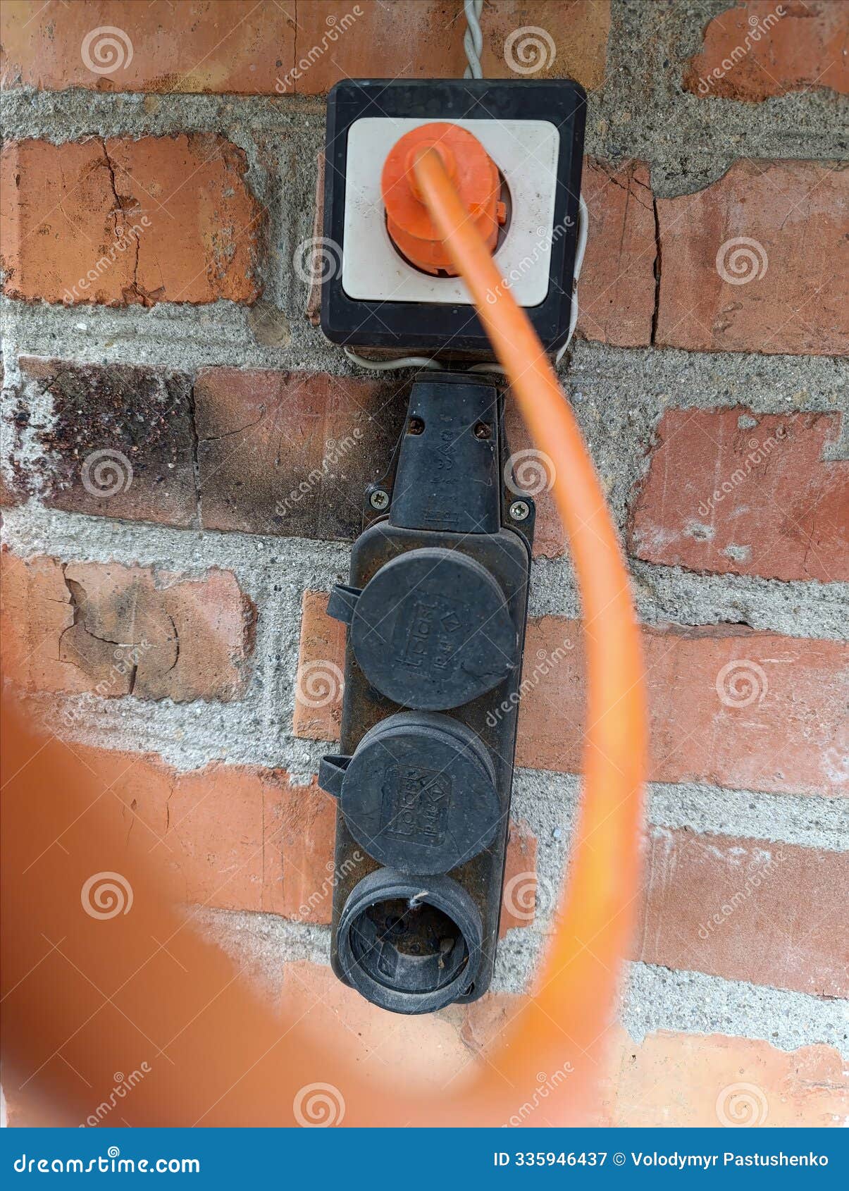 An Electrical Outlet on a Brick Wall with an Orange Cord Stock Image ...