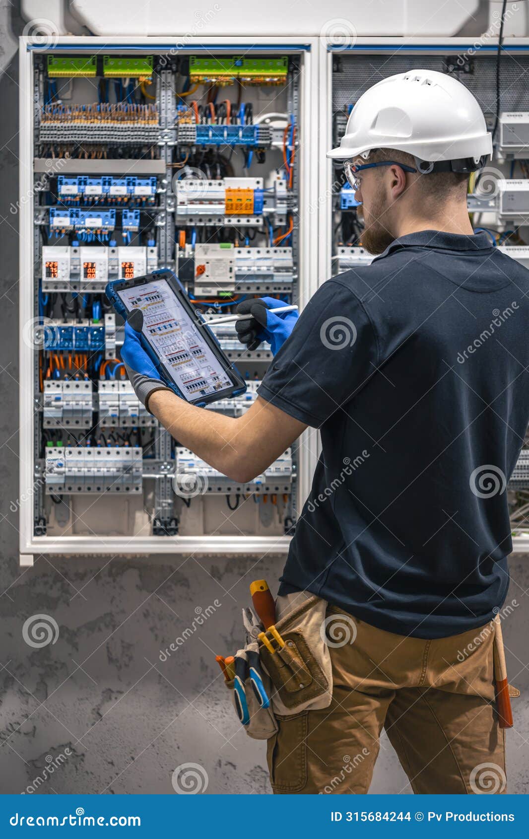 Electrical Technician Working in a Switchboard with Fuses, Uses a Tablet. Stock Photo - Image of ...