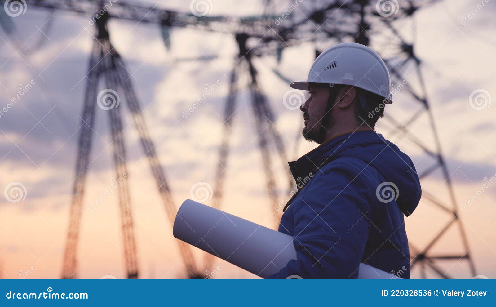 An Electrician on the Background of High Towers of Power Plants Looks ...