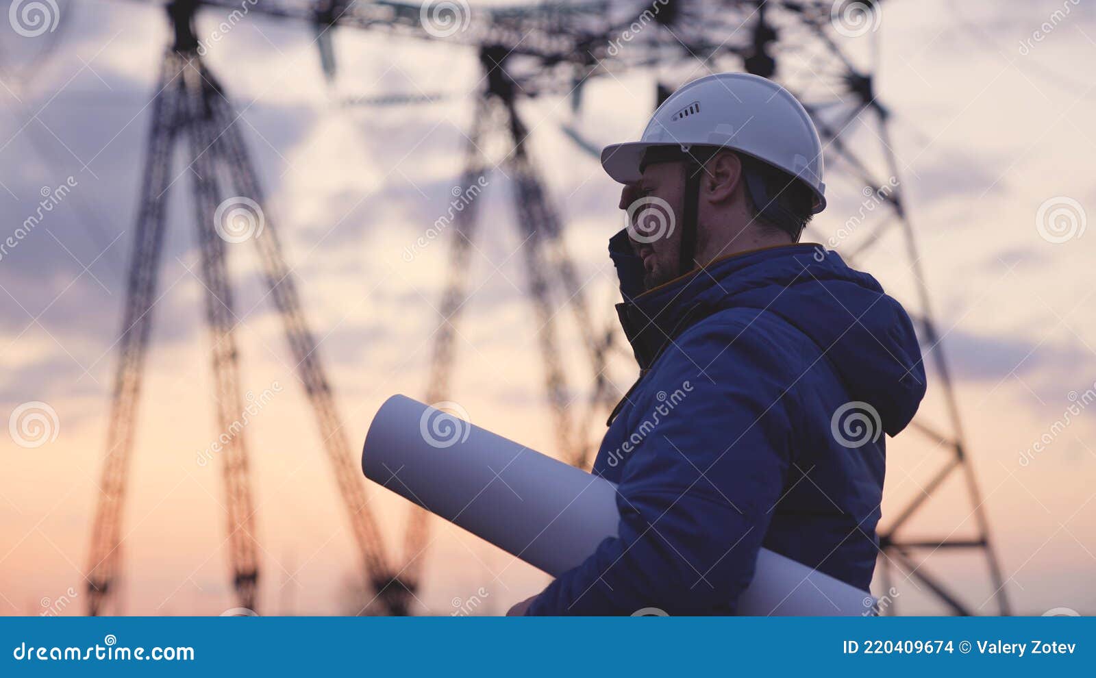 An Electrician on the Background of High Towers of Power Plants Looks ...