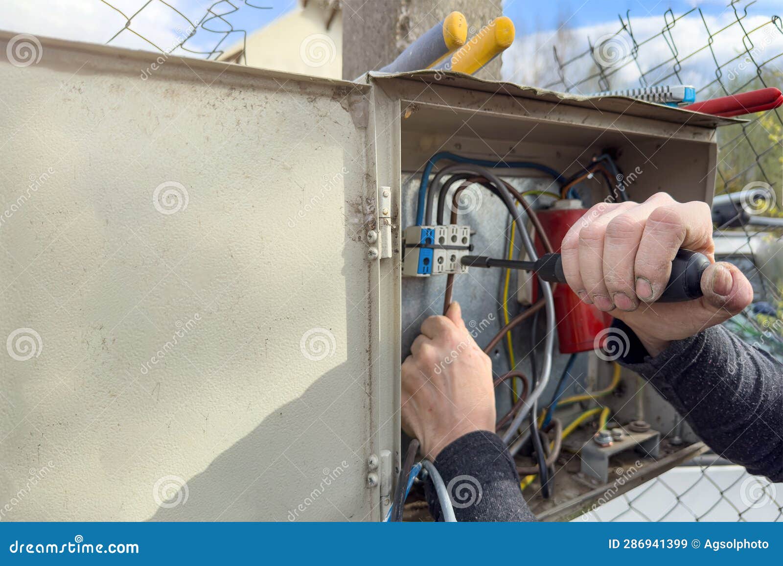 An Electrician Connects Wires in a Switchboard Outdoors. the Hands of ...