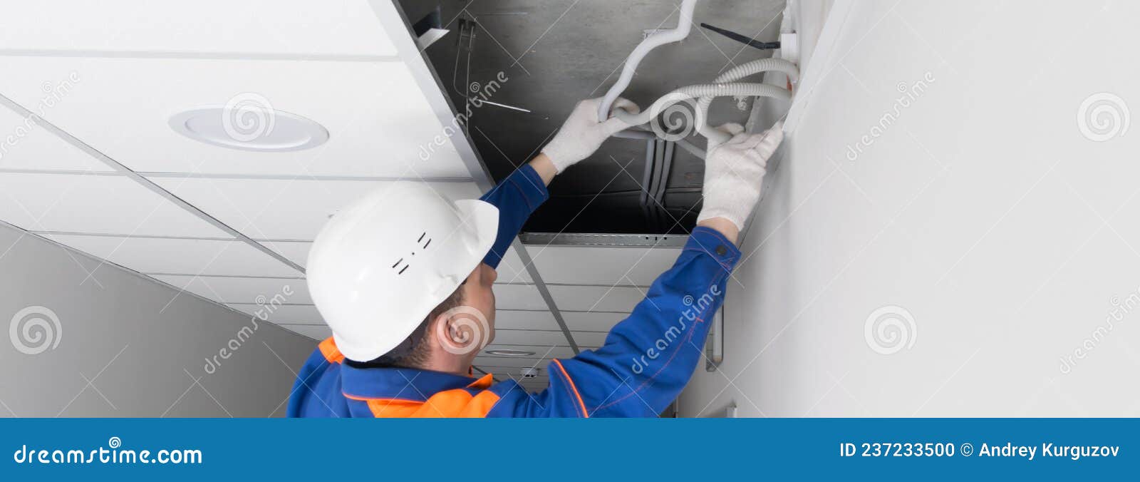 Electrician in a Protective Helmet, Fixes a Malfunction in ...