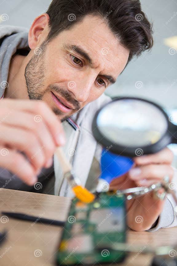 Electronics Engineer Cleaning Circuit Board through Magnifying Glass ...