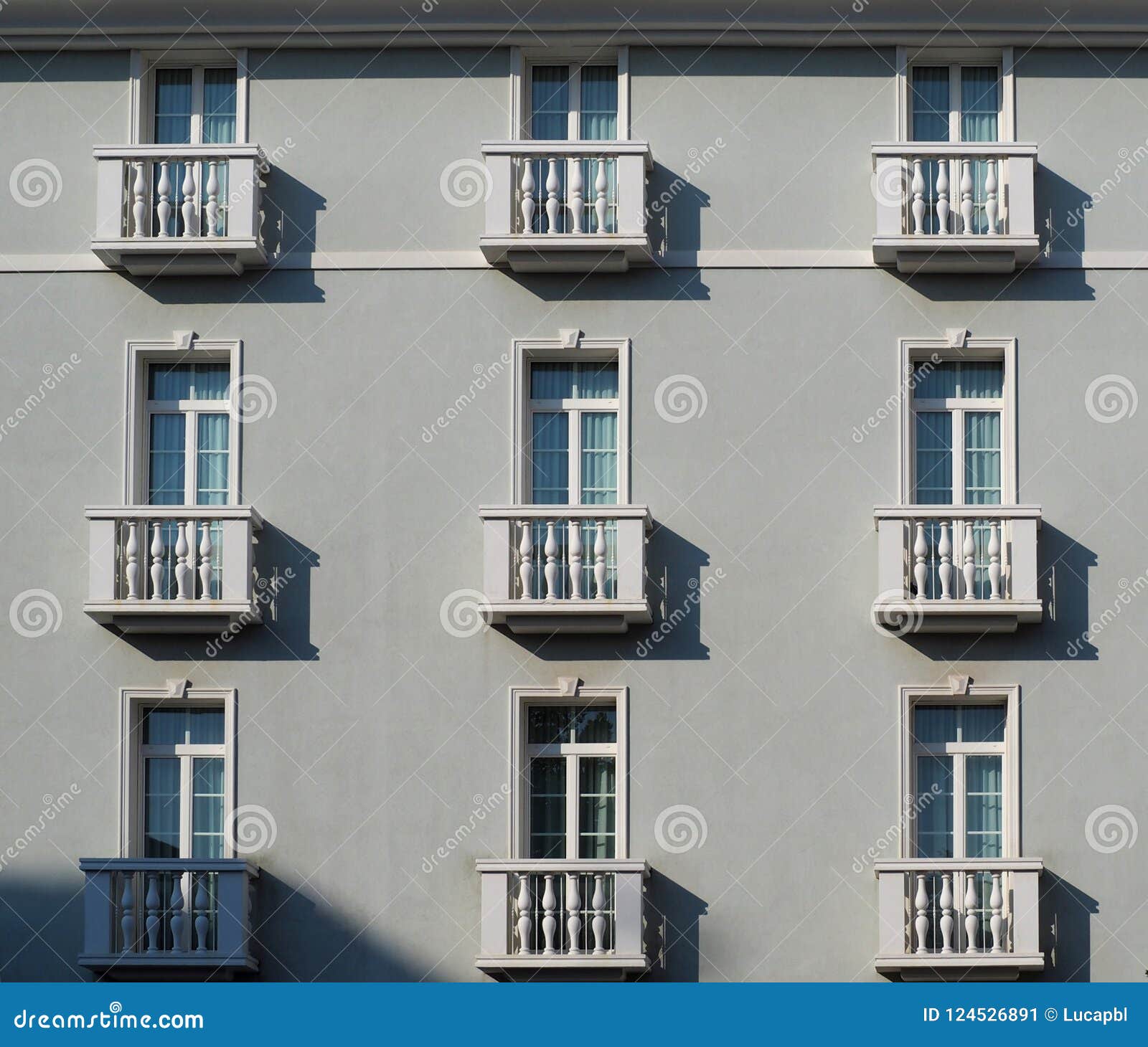 Elegant Light Grey Facade with Large Windows and Small White Balconies ...