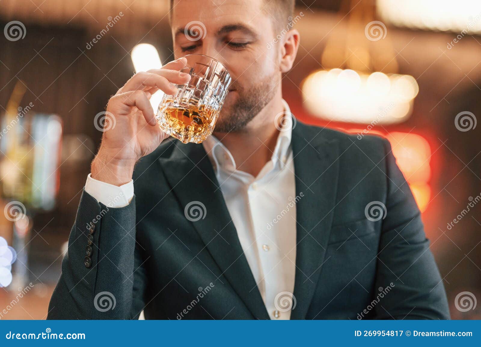An Elegant Man in Black Suit is in the Bar, Tasting the Alcohol Drink ...