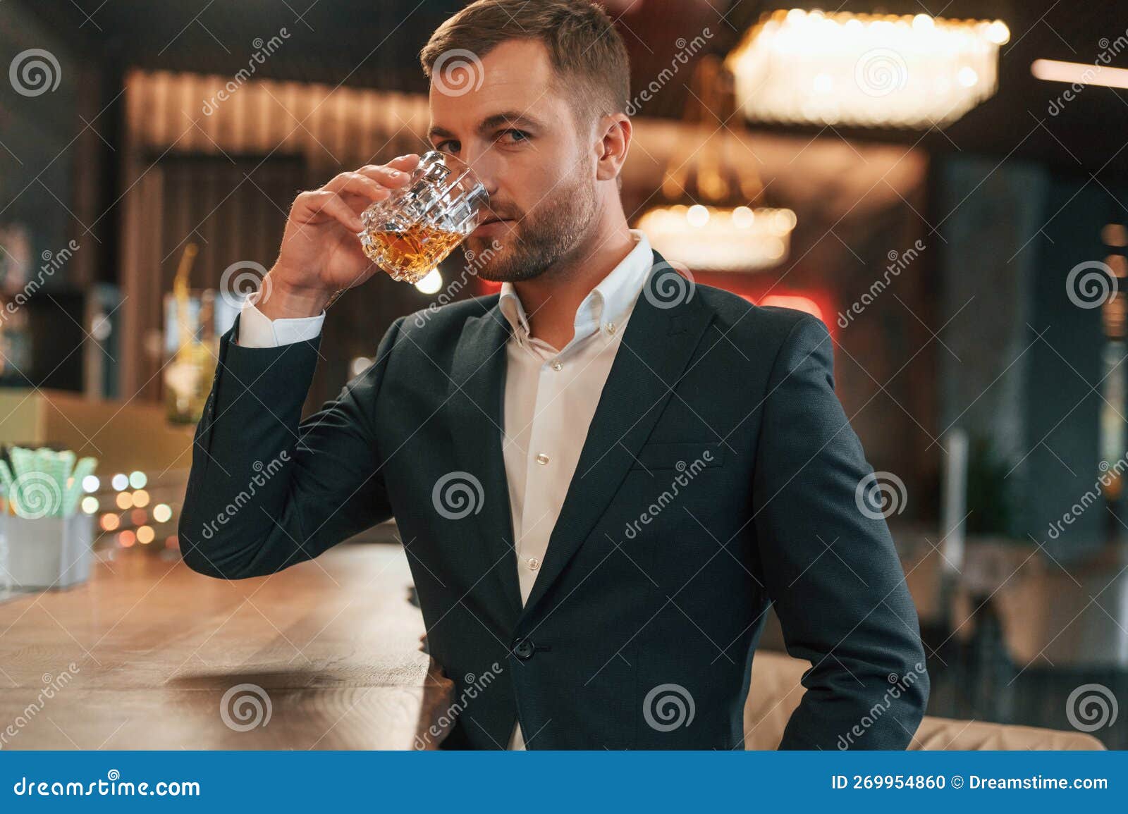 An Elegant Man in Black Suit is in the Bar, Tasting the Alcohol Drink ...