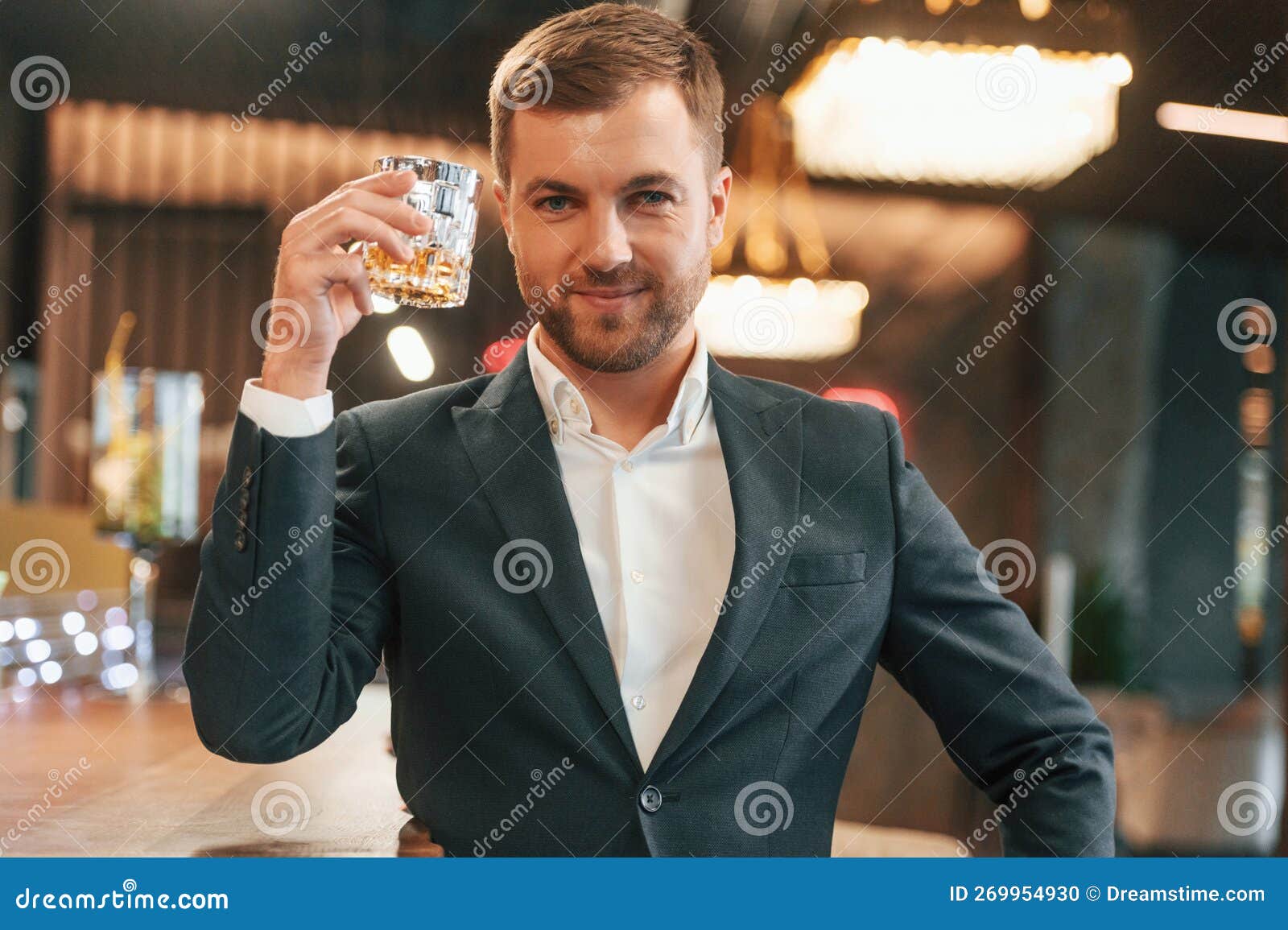 An Elegant Man in Black Suit is in the Bar, Tasting the Alcohol Drink ...