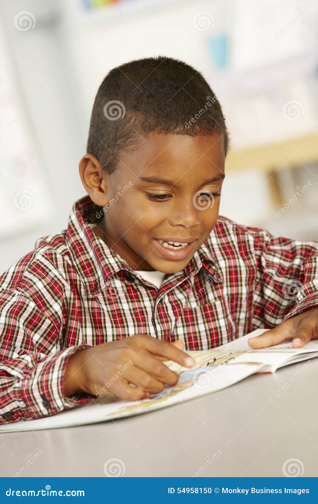 Elementary Age Schoolboy Reading Book in Class Stock Photo - Image of ...