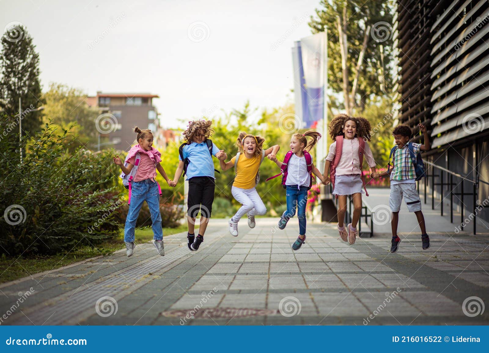 Elementary Age Schoolchildren Jumping in Schoolyard Stock Photo - Image ...